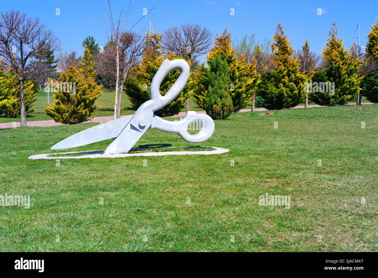 Statue of huge Scissor on the grass at park in a sunny summer day with ...