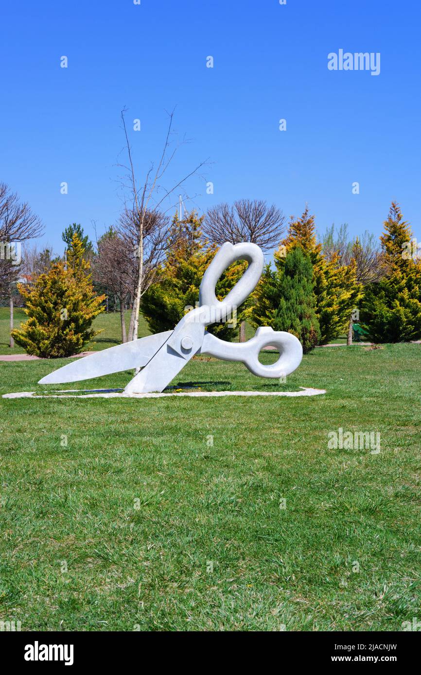 Statue of huge Scissor on the grass at park in a sunny summer day with ...