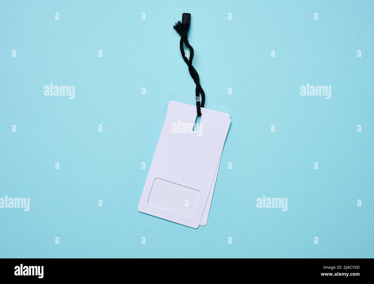 Blank rectangular paper white price tag with black rope on a blue ...