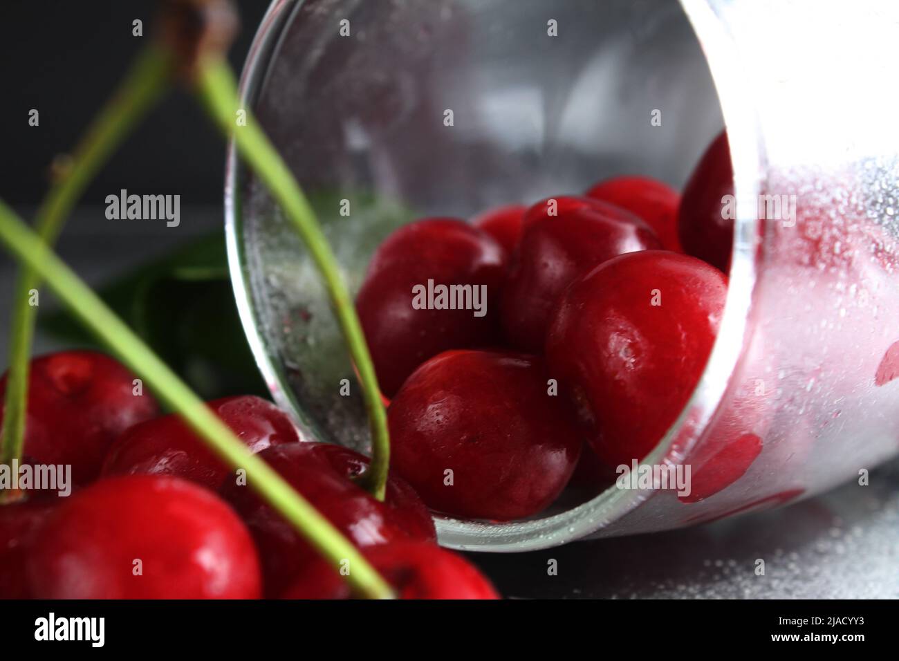cherry red ripe berry fell out of the glass on a black background with ...