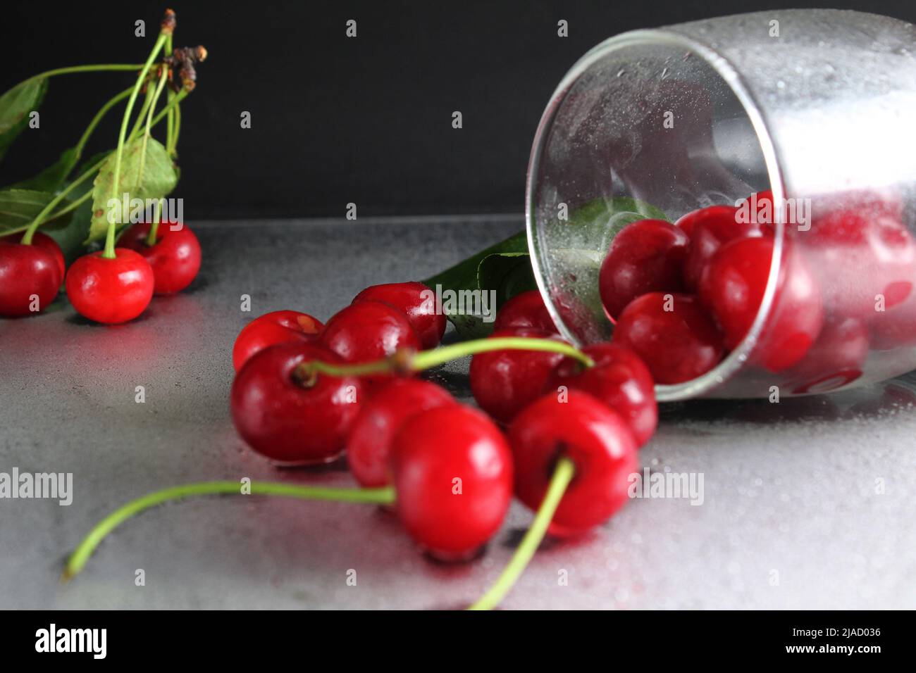 cherry red ripe berry fell out of the glass on a black background with ...