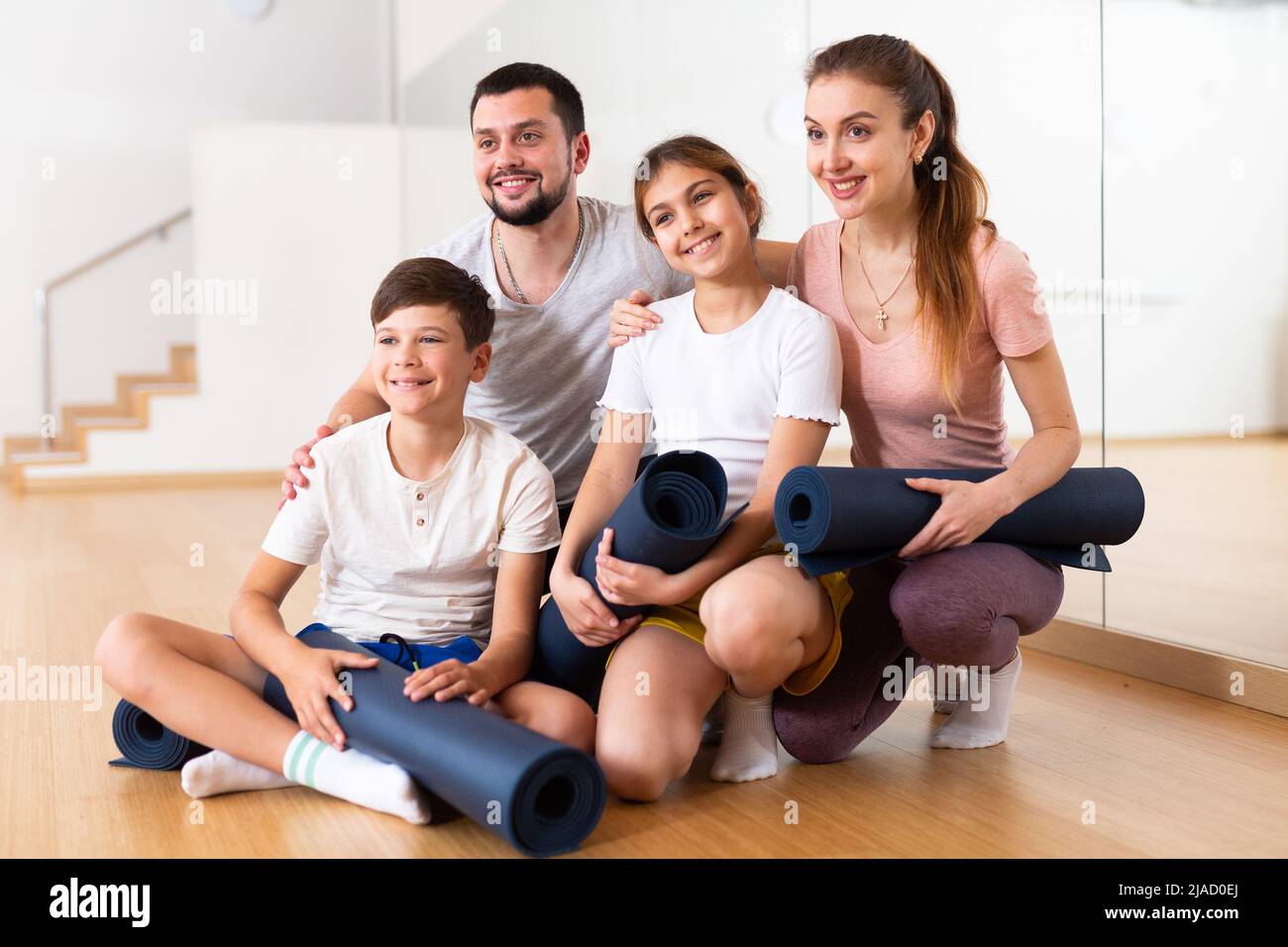 Happy family with rolled mats in gym Stock Photo - Alamy