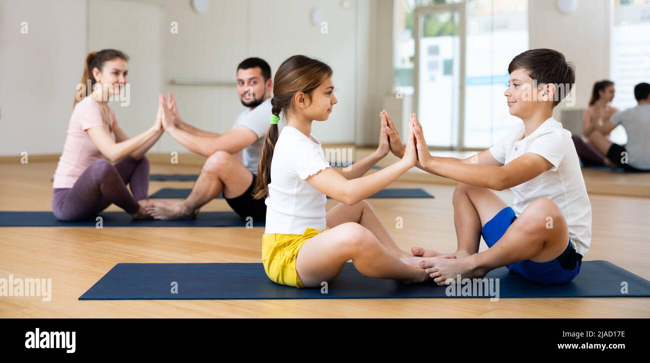 Kids and parents sitting back to back on mats Stock Photo - Alamy