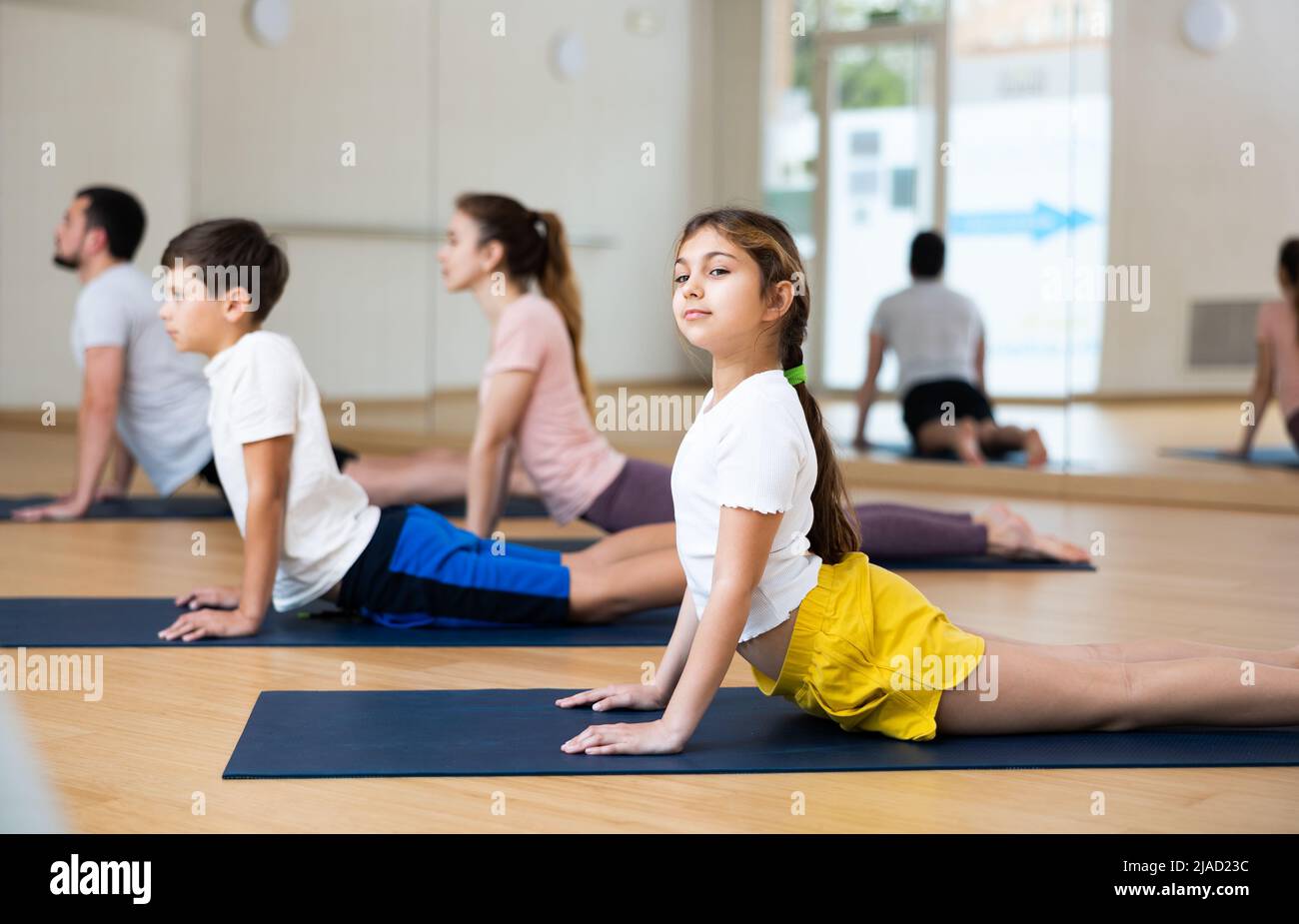 Girl doing stretching asana Upward Facing Dog during family yoga ...