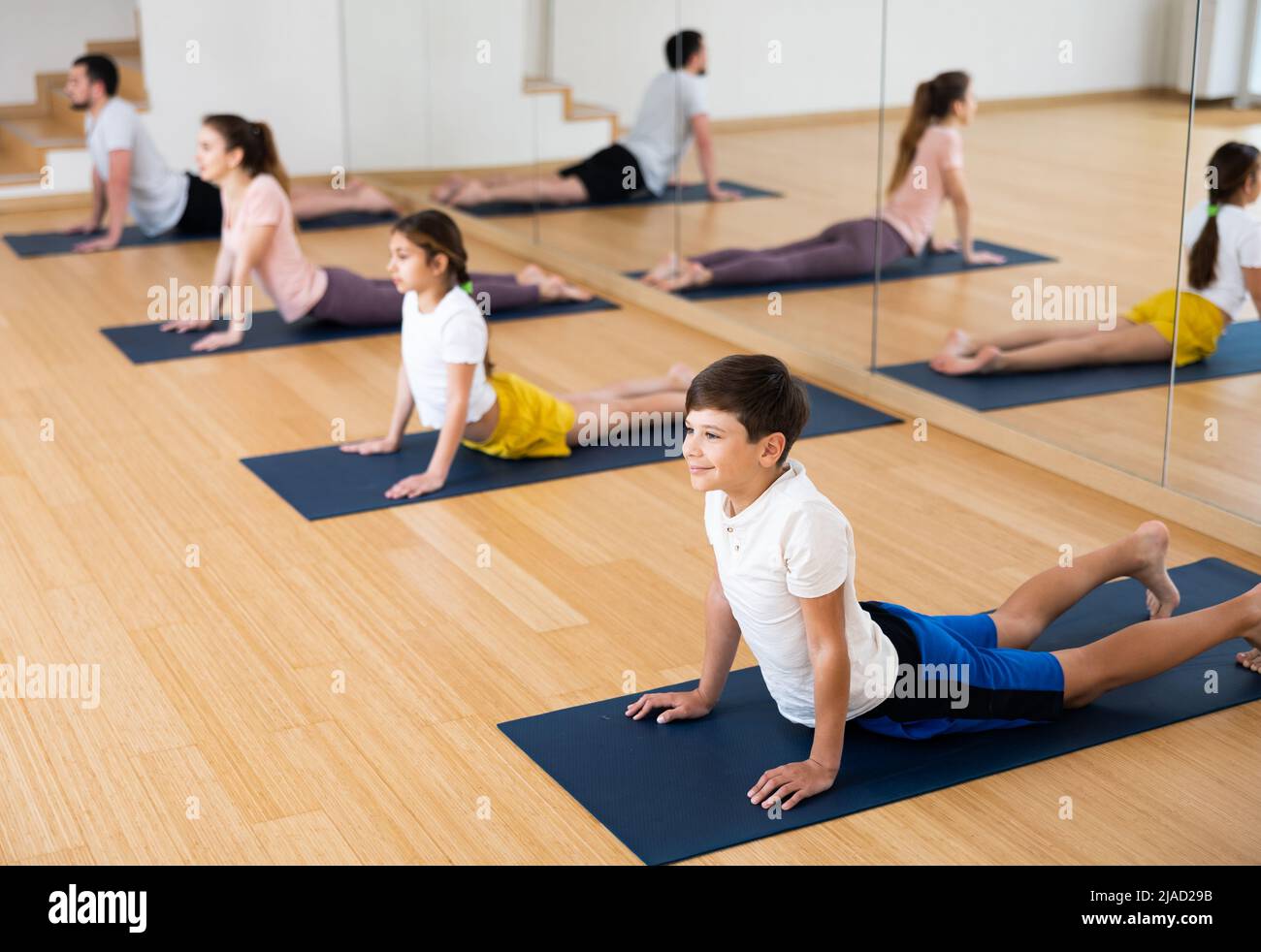 Boy doing stretching asana Bhujangasana during family yoga class Stock ...