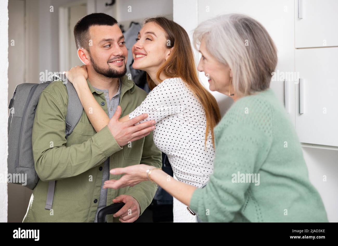 Woman and her mother welcoming man at home Stock Photo - Alamy