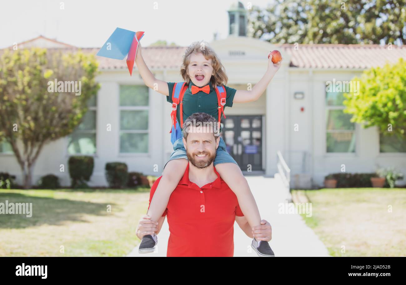 Man and excited amazed child son piggyback near school. Father and son ...