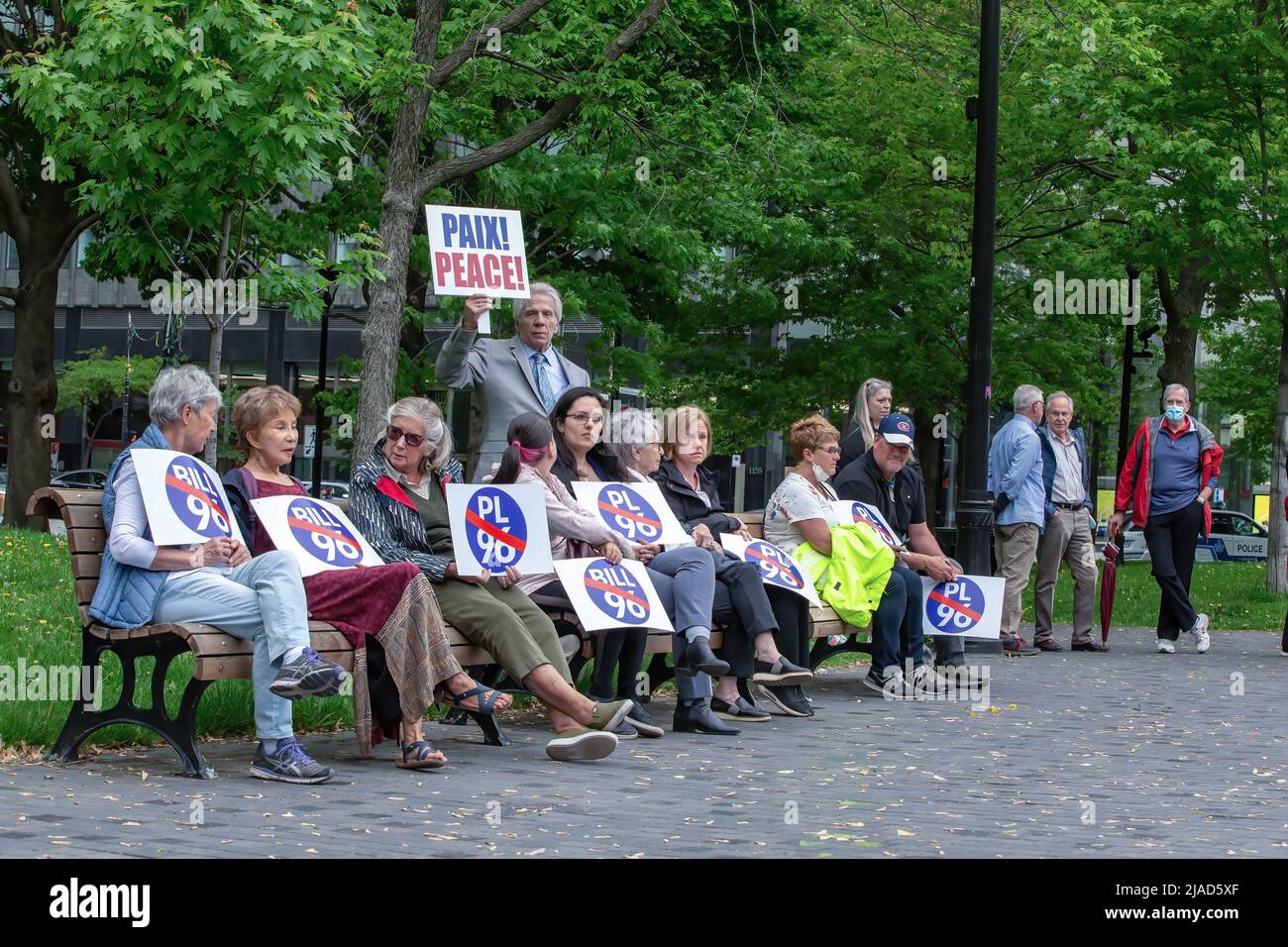 A group of elderly protesters are seen seated by the road with signs ...