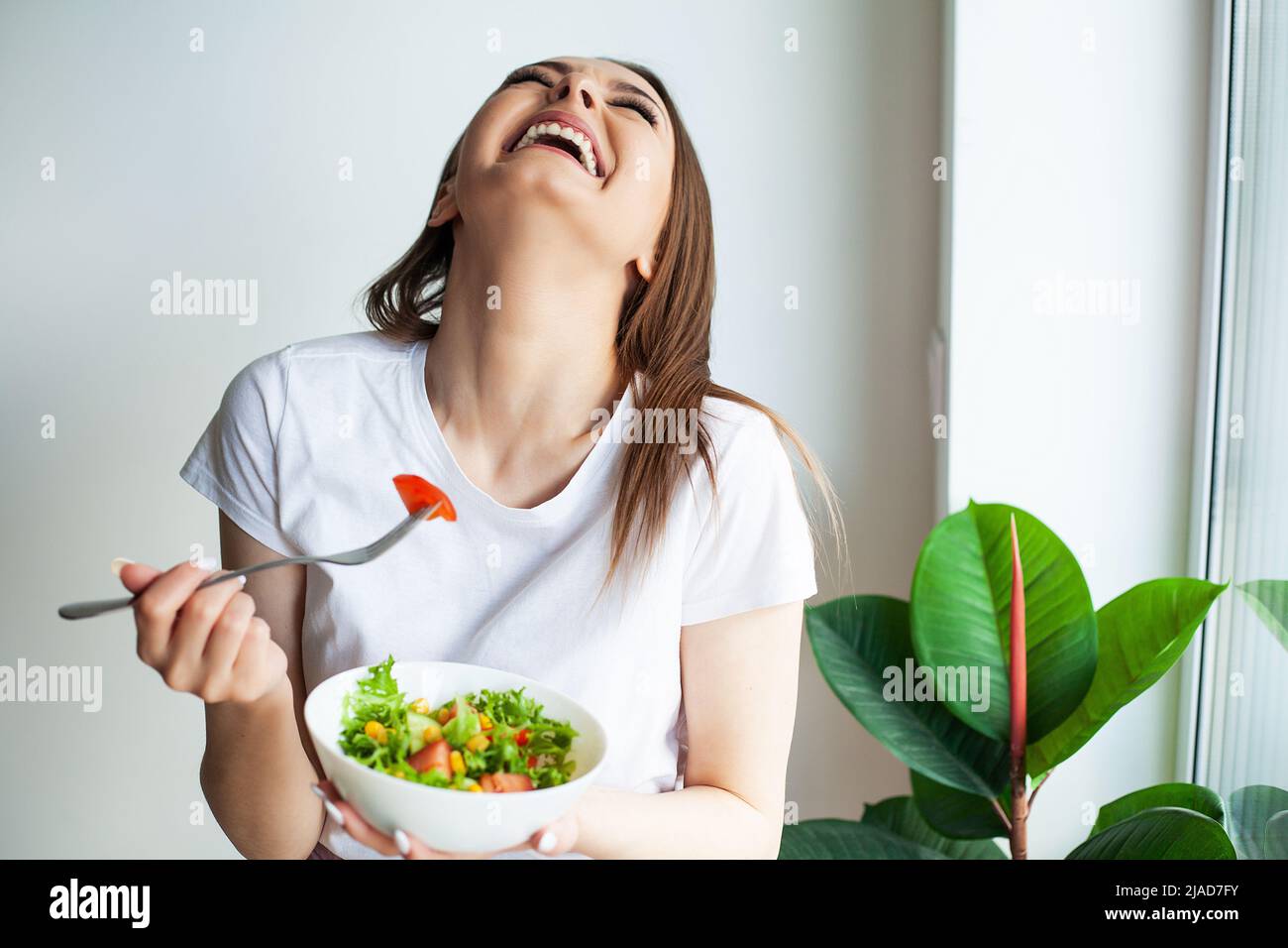 Healthy lifestyle woman eating salad smiling happy in light kitchen ...