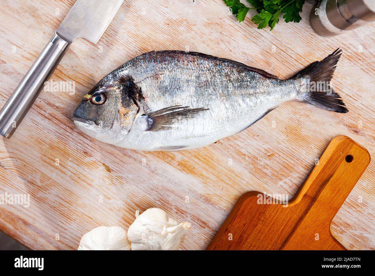 Raw whole dorado fish with garlic and greens, nobody Stock Photo - Alamy