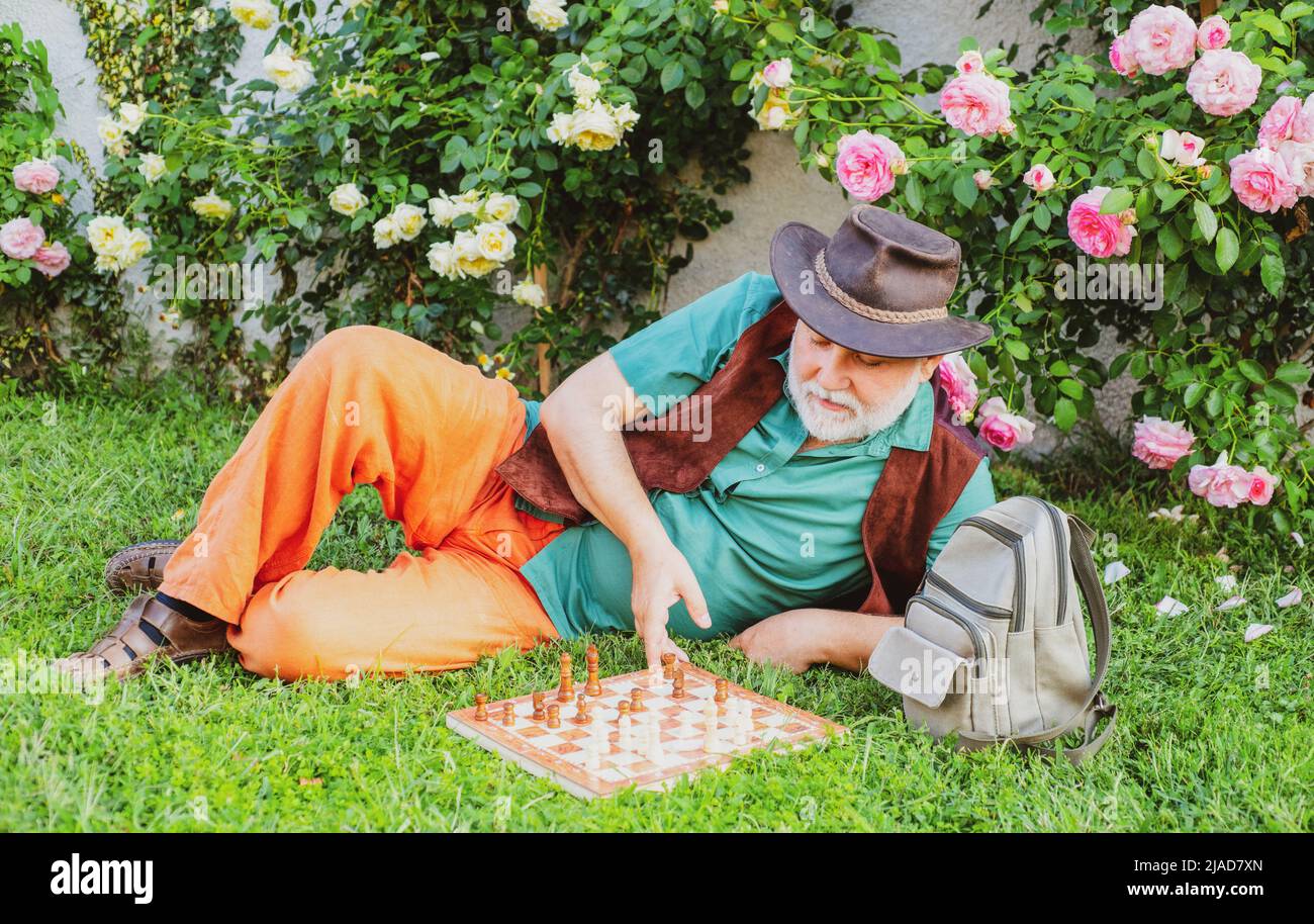 Old man in spring rosesgarden with chess. Hobby concept. Happy old age ...