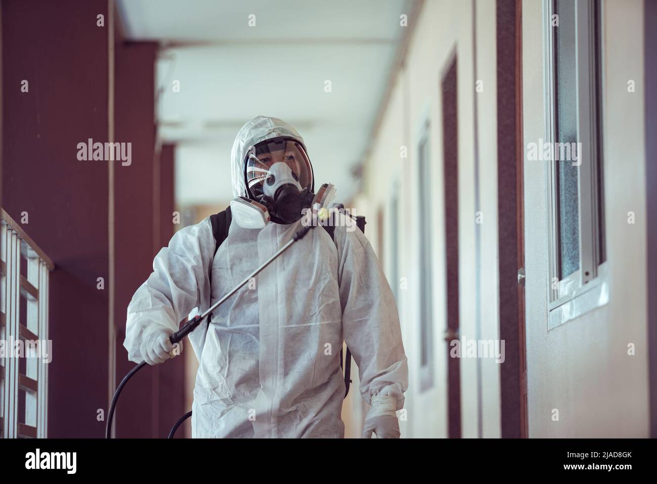 Cleaner in PPE spraying disinfectant inside a building Stock Photo - Alamy