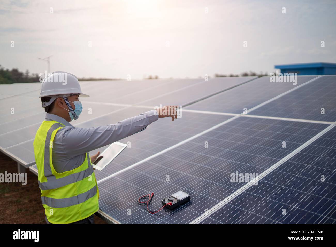Engineer with a digital tablet standing next to solar panels at a solar ...