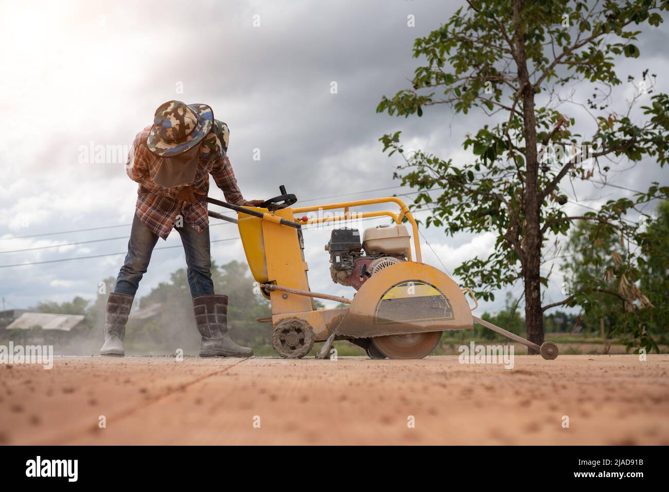 Construction worker using road cutting machinery to cut road surface ...