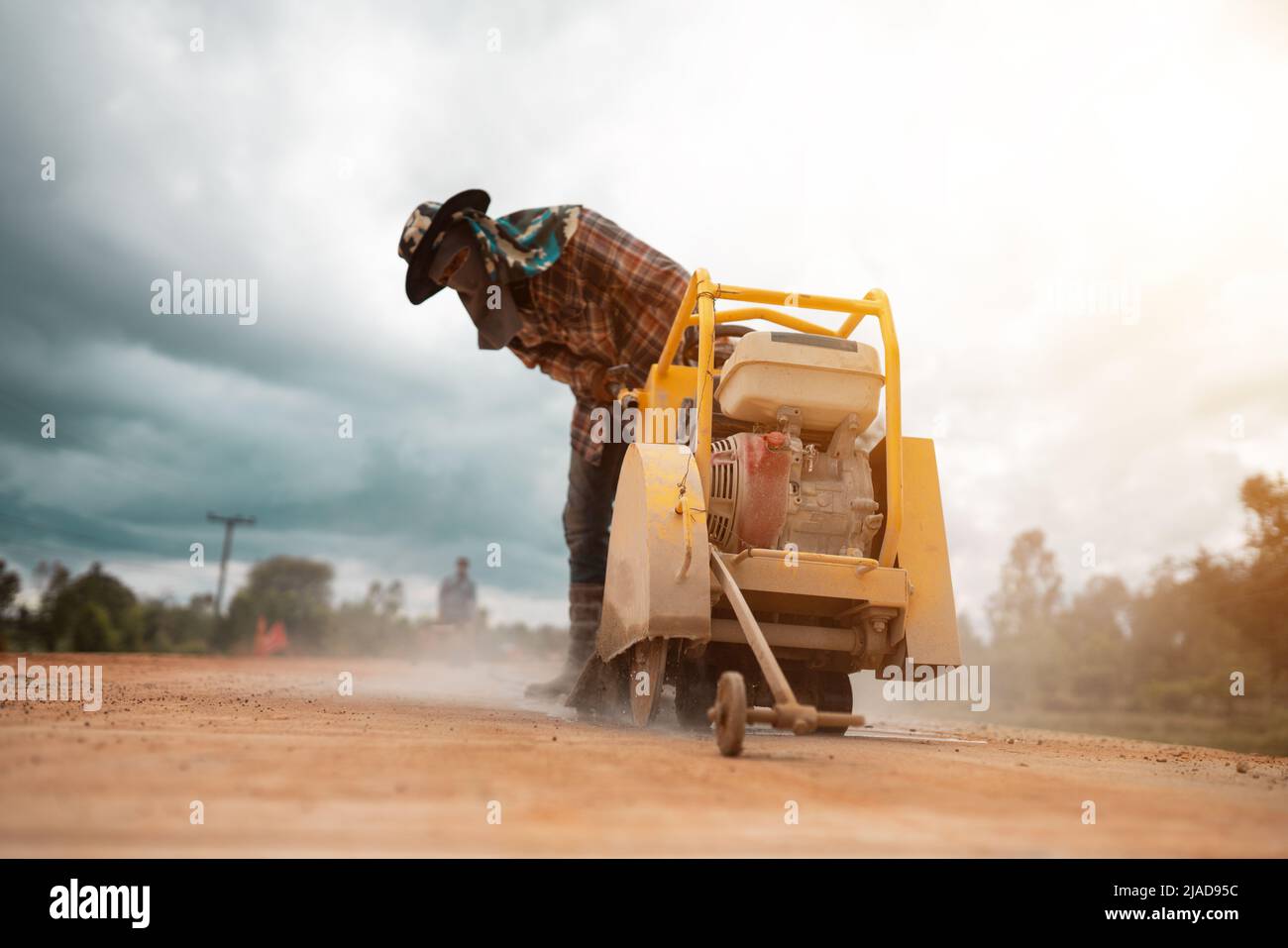 Construction worker using road cutting machinery to cut road surface ...