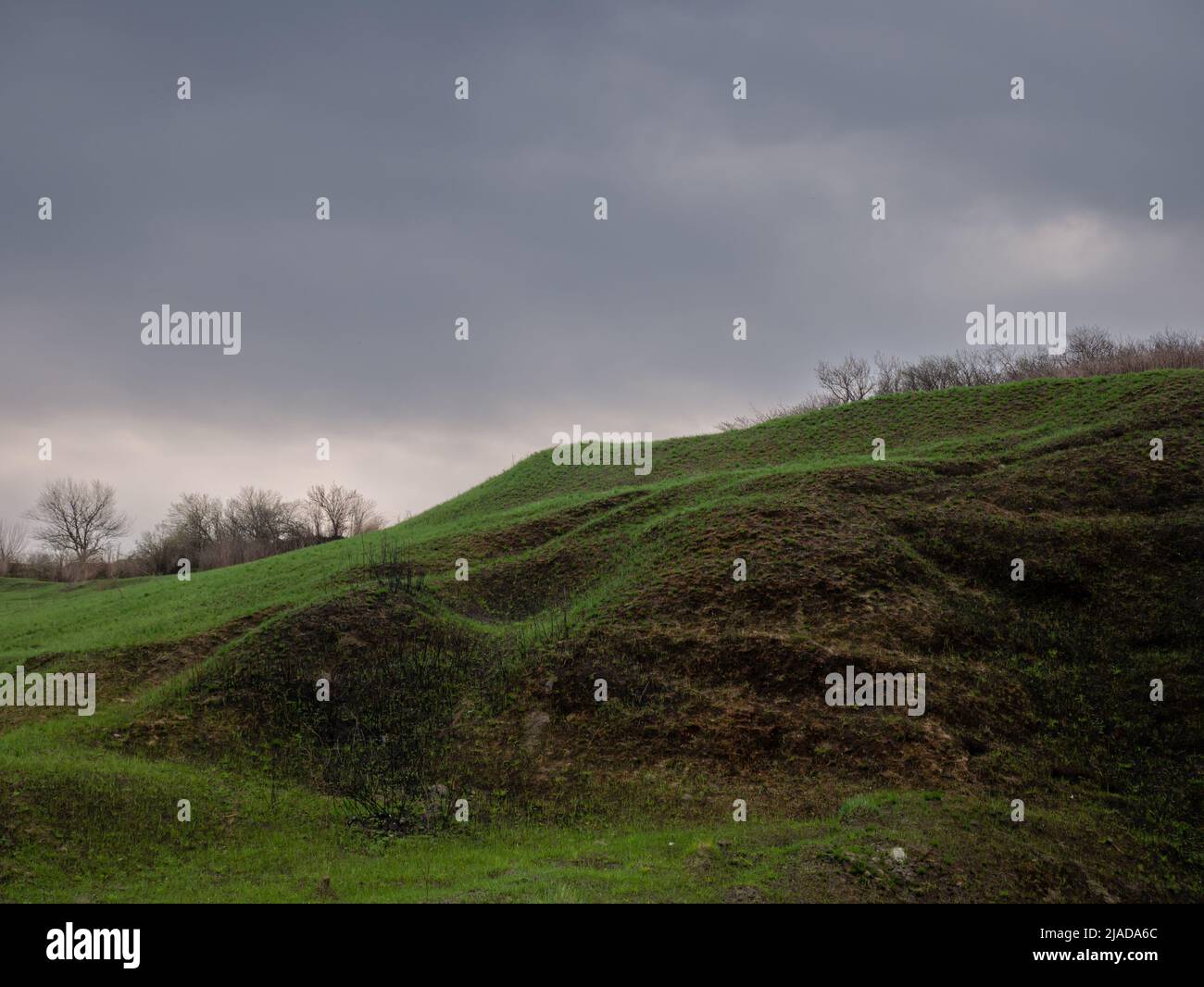 Green grass hills landscape with cloudy dark sky. Outdoor nature back ...