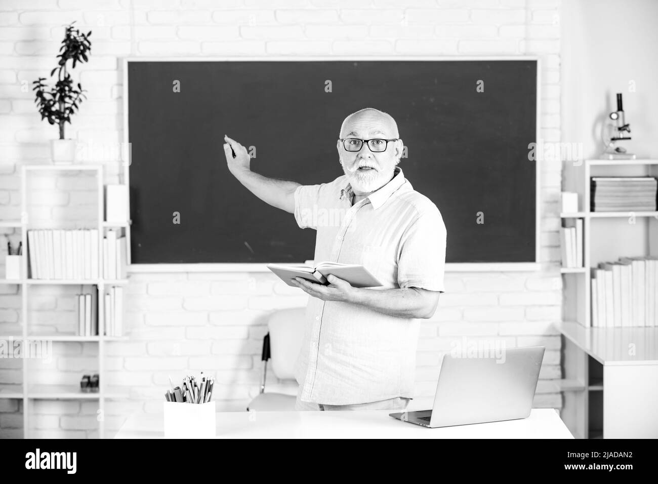 Portrait of senior teacher teaching line of high school students with ...