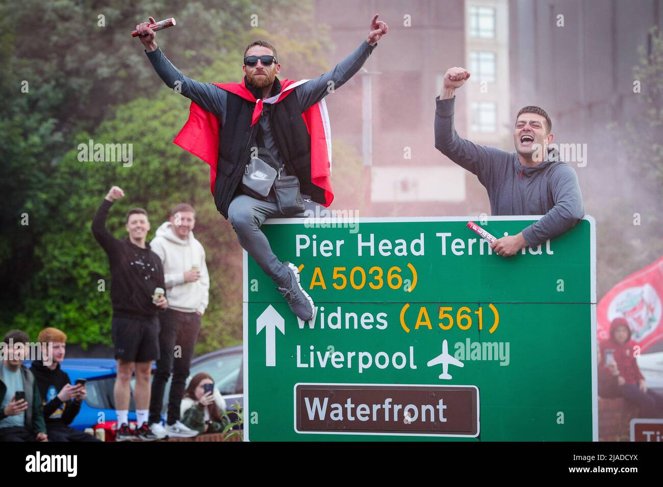 Supporters climb on street signs and set of flares as the Liverpool FC ...