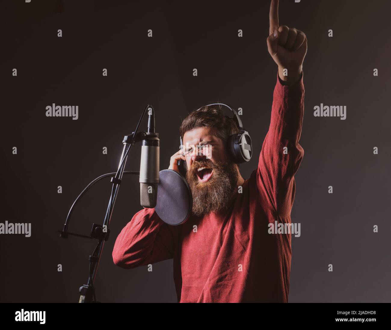 Singer with expression face wearing headphones is performing a song ...