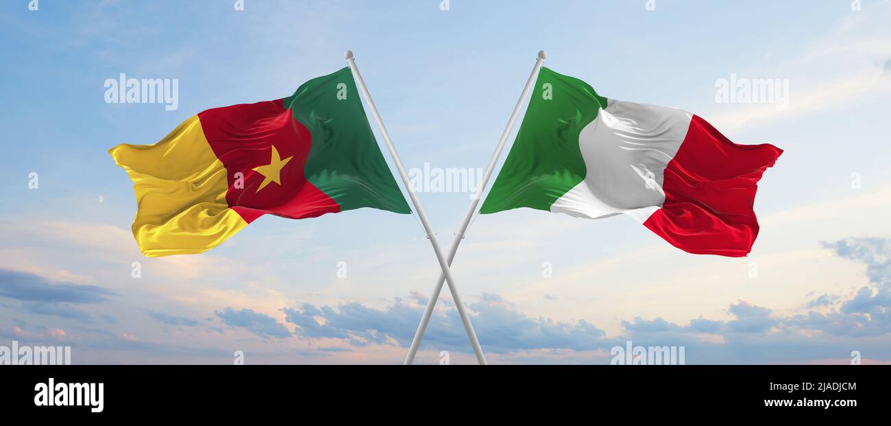 two crossed flags Cameroon and Italy waving in wind at cloudy sky ...