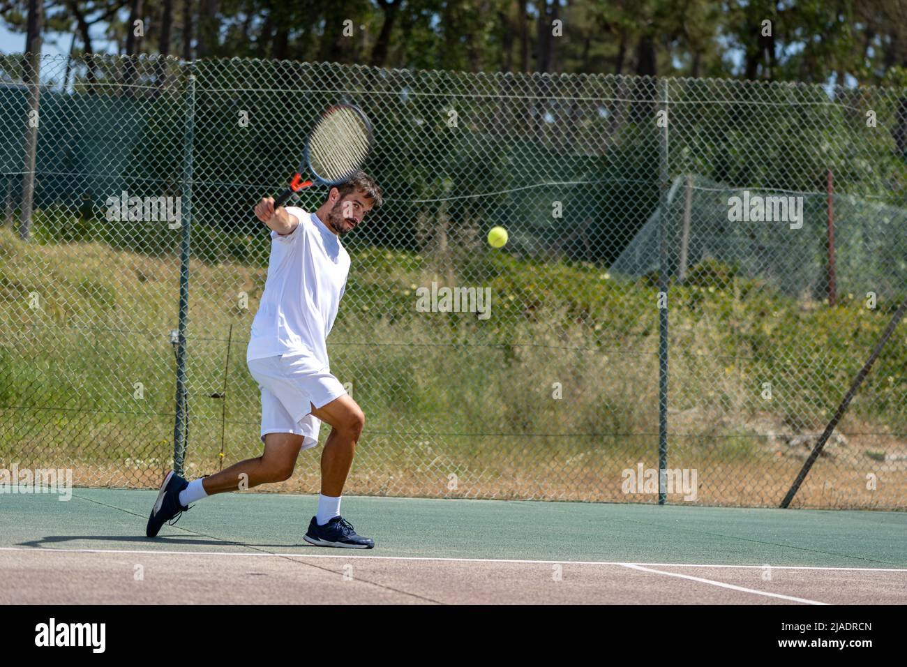 Tennis player hitting backhand at ball with racket on court Stock Photo ...