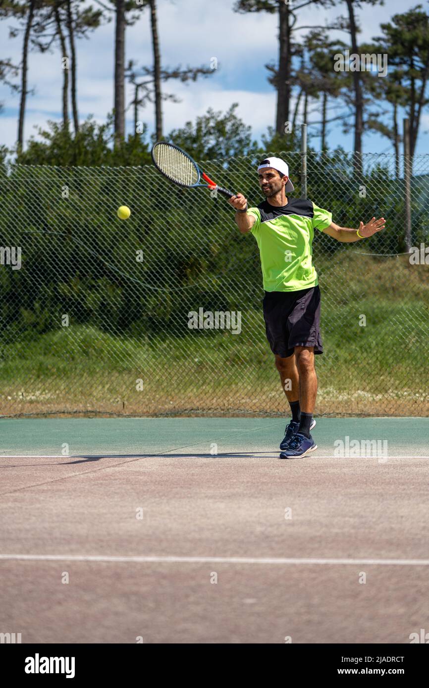 Tennis player hitting forehand at ball with racket on court Stock Photo ...