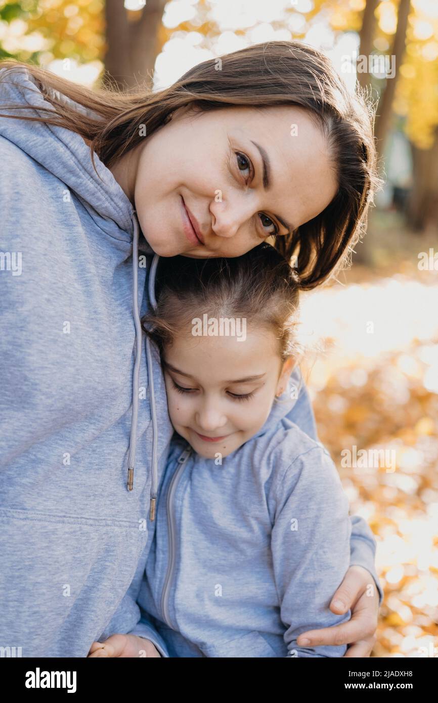 Close-up portrait of mother hugging daughter in park. Smiling happy child. Family care. Family ...