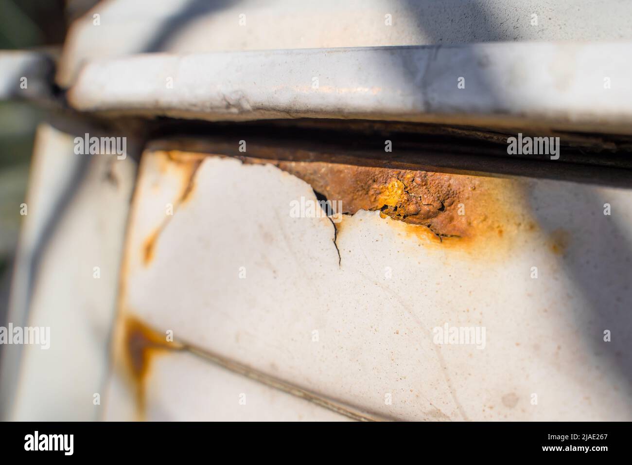 Rust pockets on the wing of a white car close-up. The effect of ...
