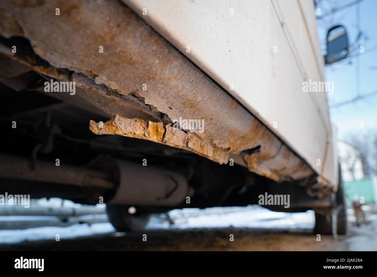 Rusted through the threshold of a white car close-up. Corrosion of the bottom of the car after ...