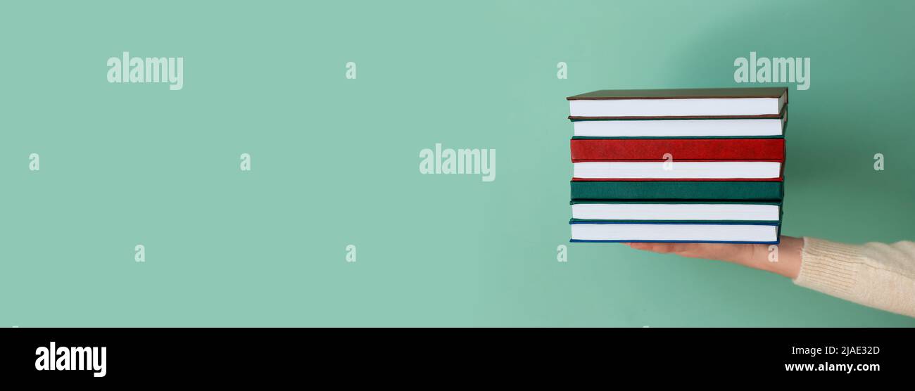 Hand holding stack of books on color background with space for text ...