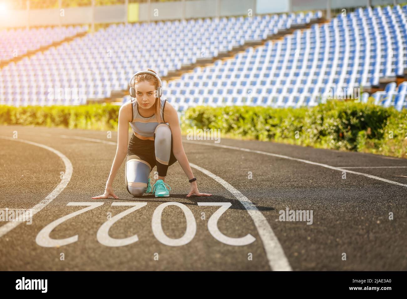 Sporty young woman in crouch start position near figure 2022 on running ...