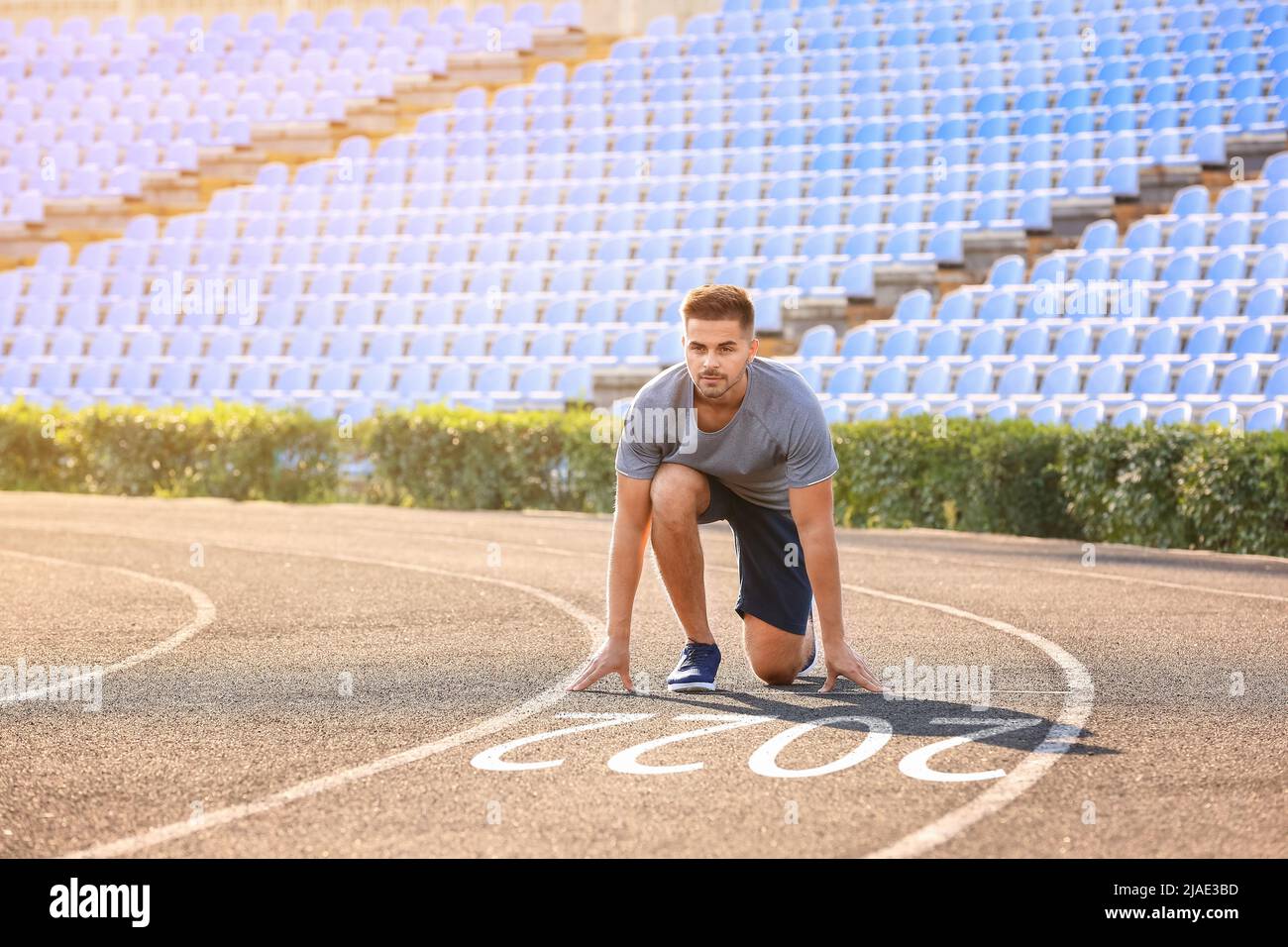 Sporty young man in crouch start position near figure 2022 on running ...