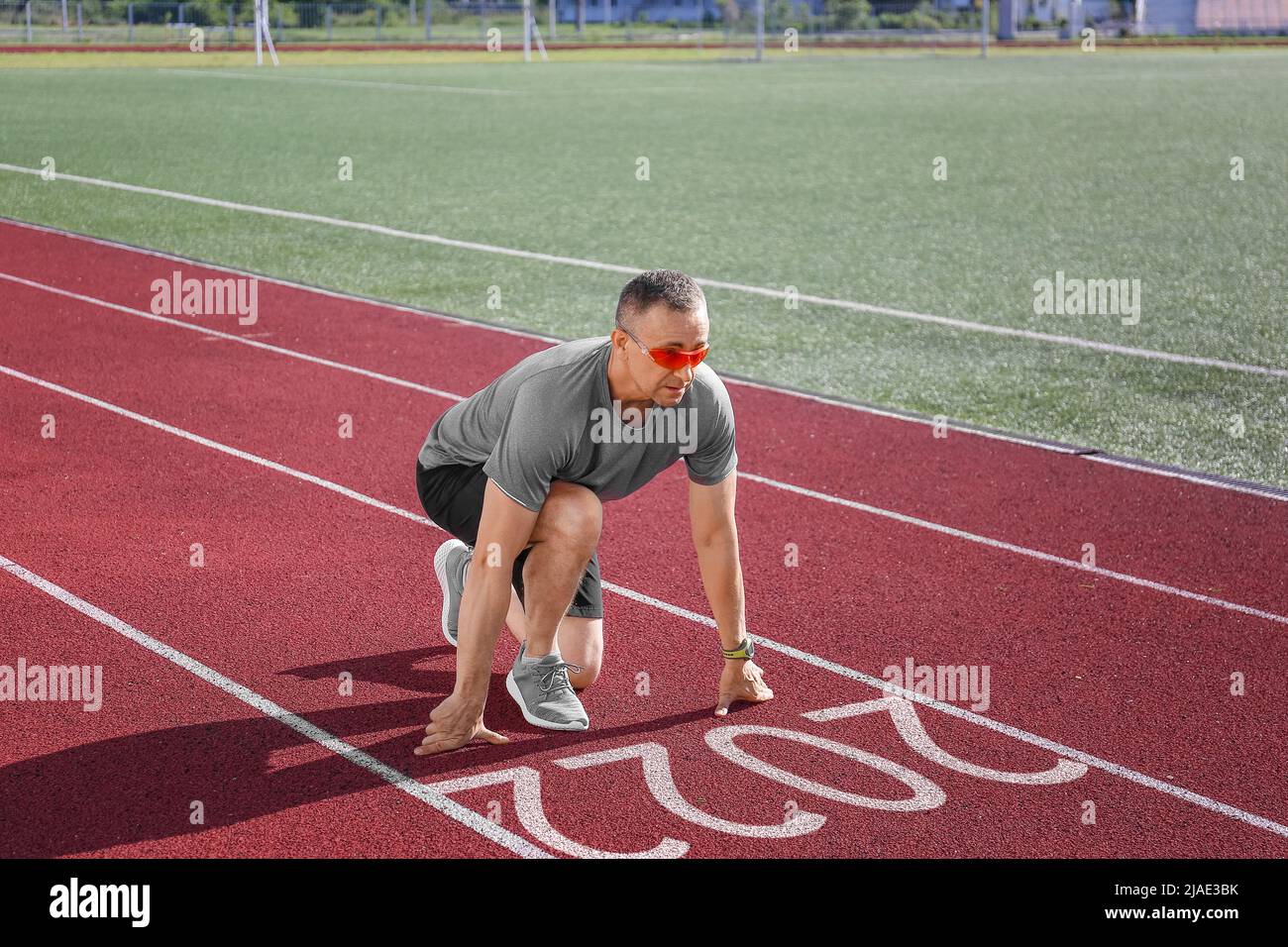 Sporty mature man in crouch start position at the stadium. Concept of ...