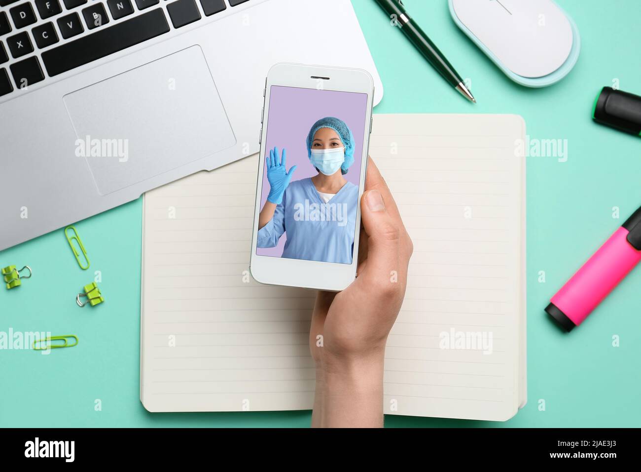 Woman holding smartphone with doctor on screen at table, top view ...