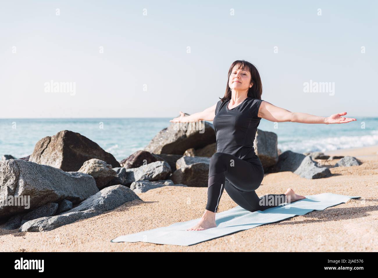 Full body of content flexible female standing in Anjaneyasana with ...