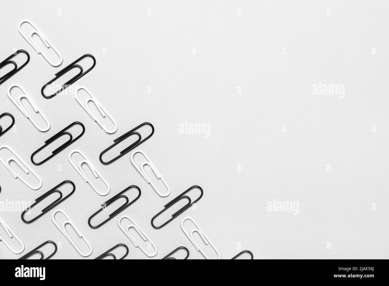 Black and white paper clips on light background Stock Photo - Alamy