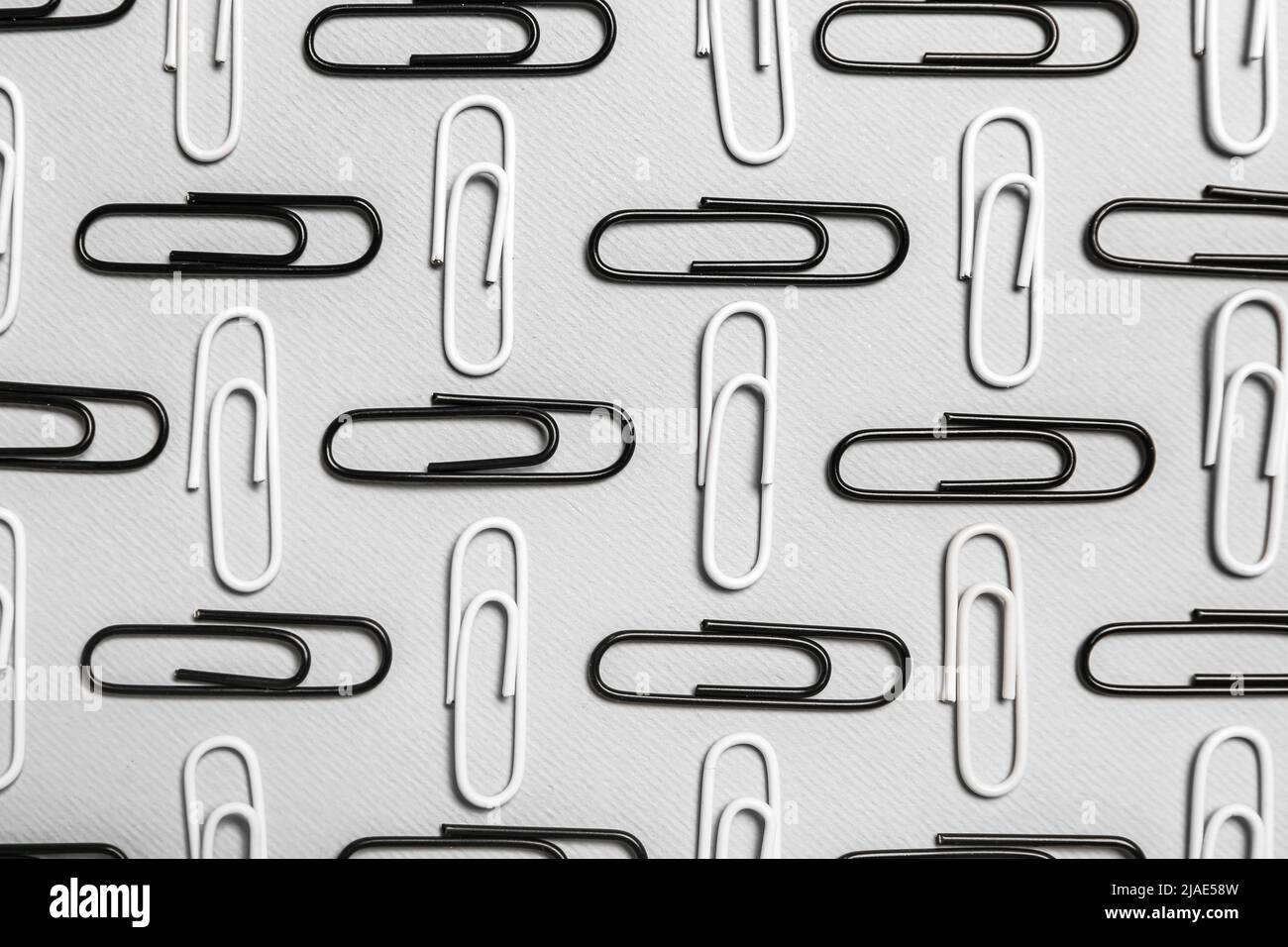 Black and white paper clips on light background Stock Photo - Alamy