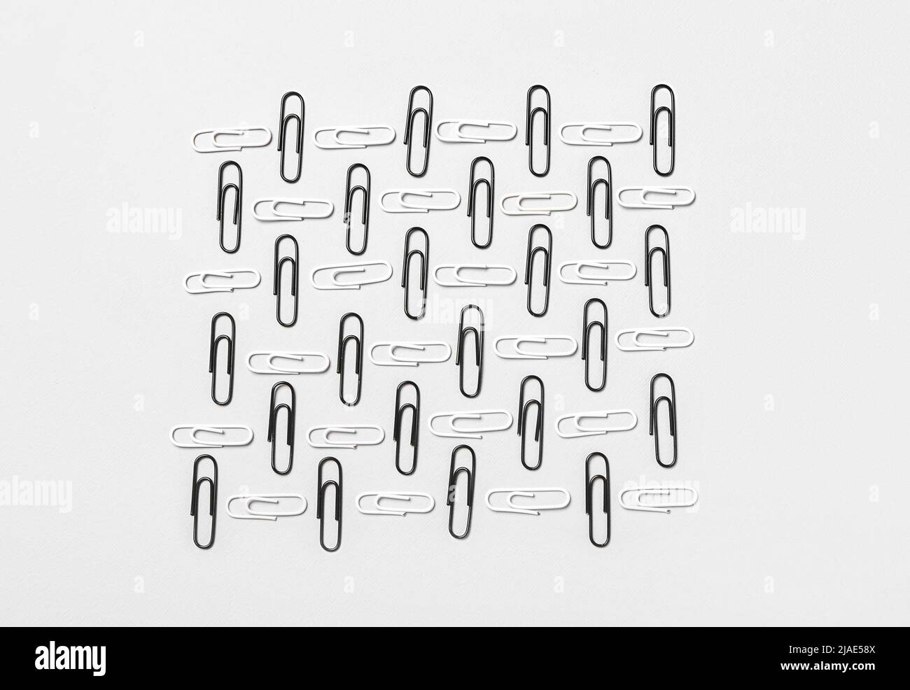 Black and white paper clips on light background Stock Photo - Alamy