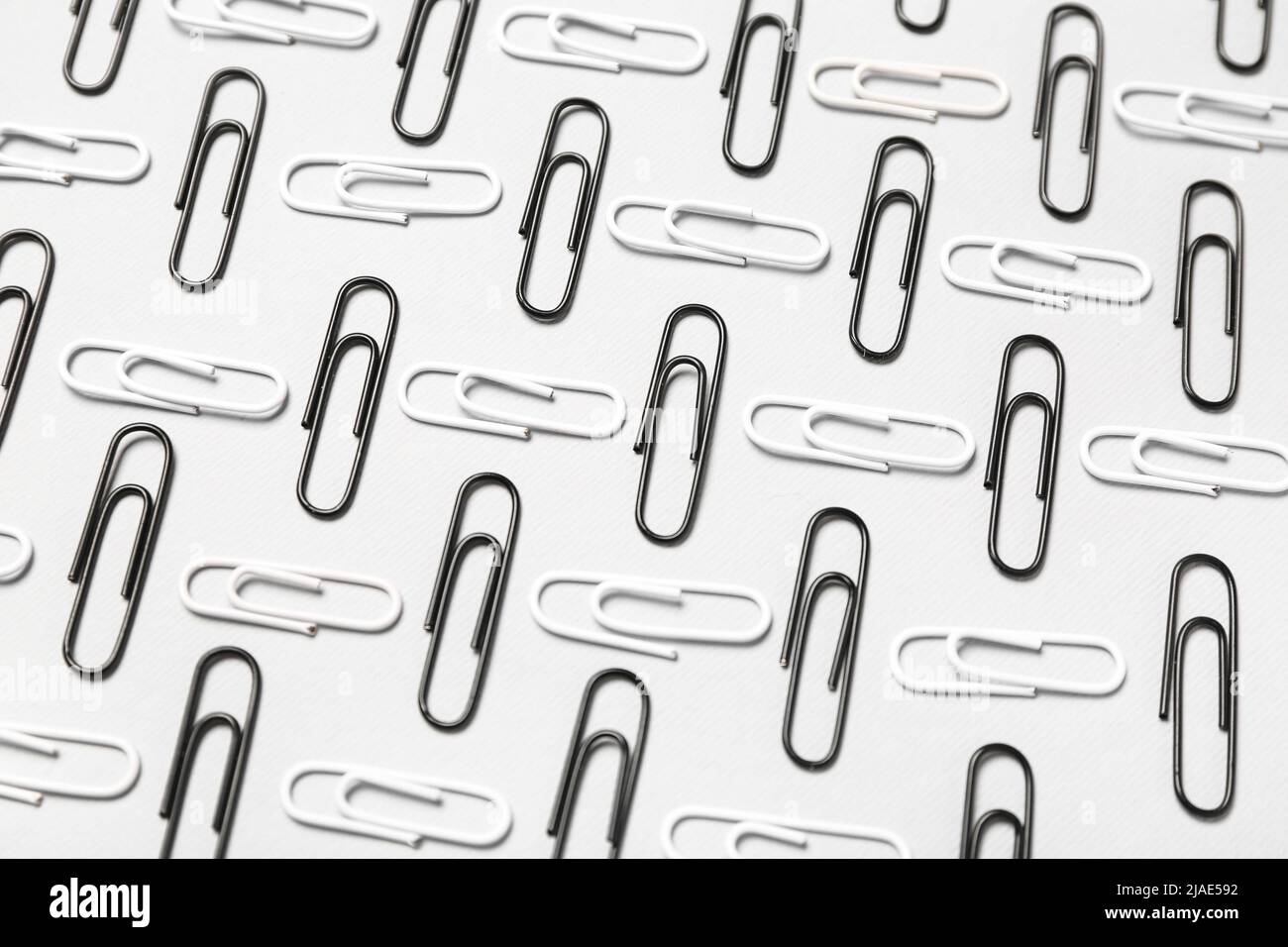 Black and white paper clips on light background Stock Photo - Alamy