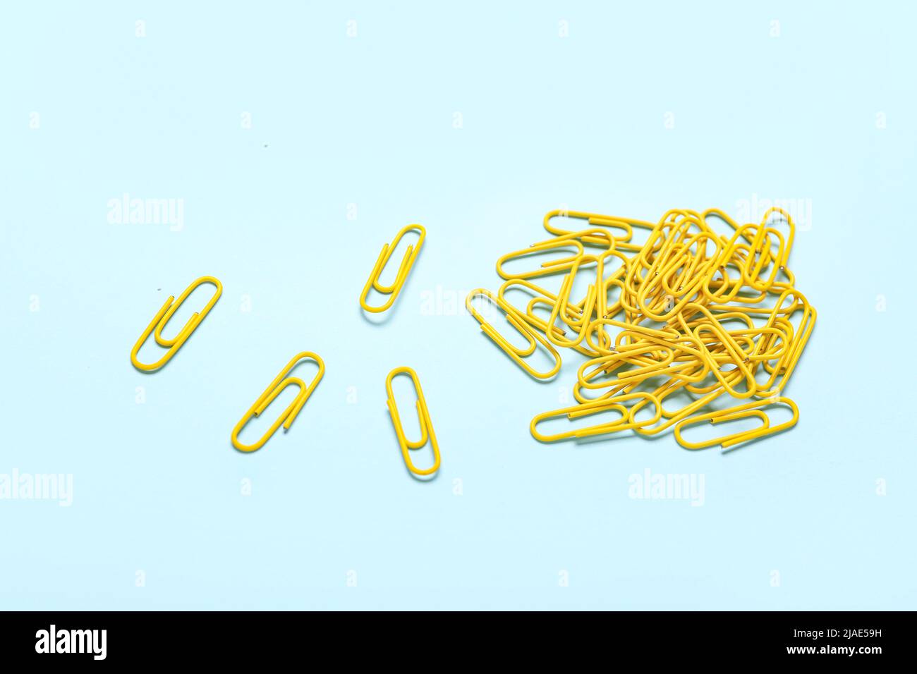 Yellow paper clips on blue background Stock Photo - Alamy