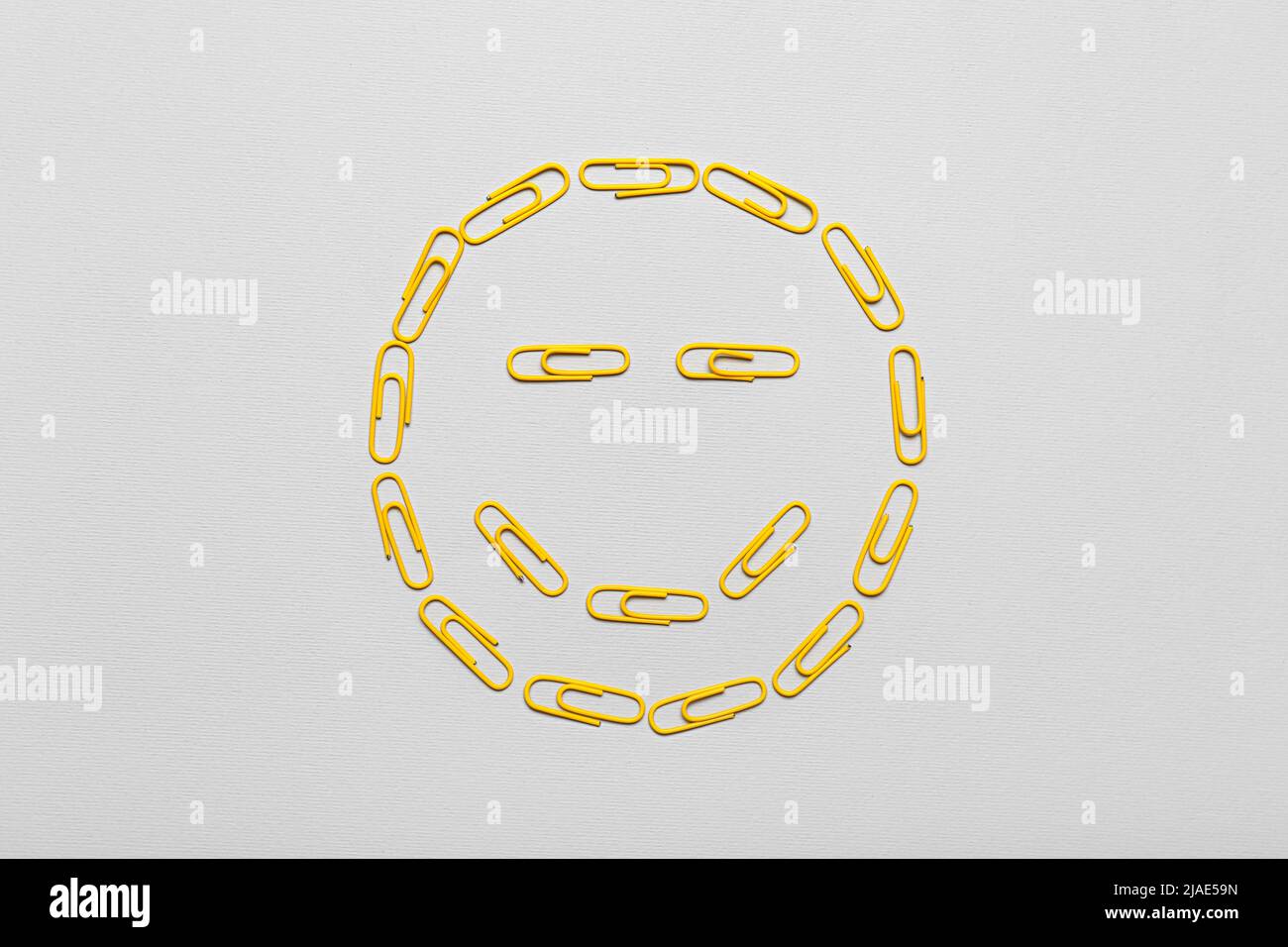 Smile made of yellow paper clips on light background Stock Photo - Alamy