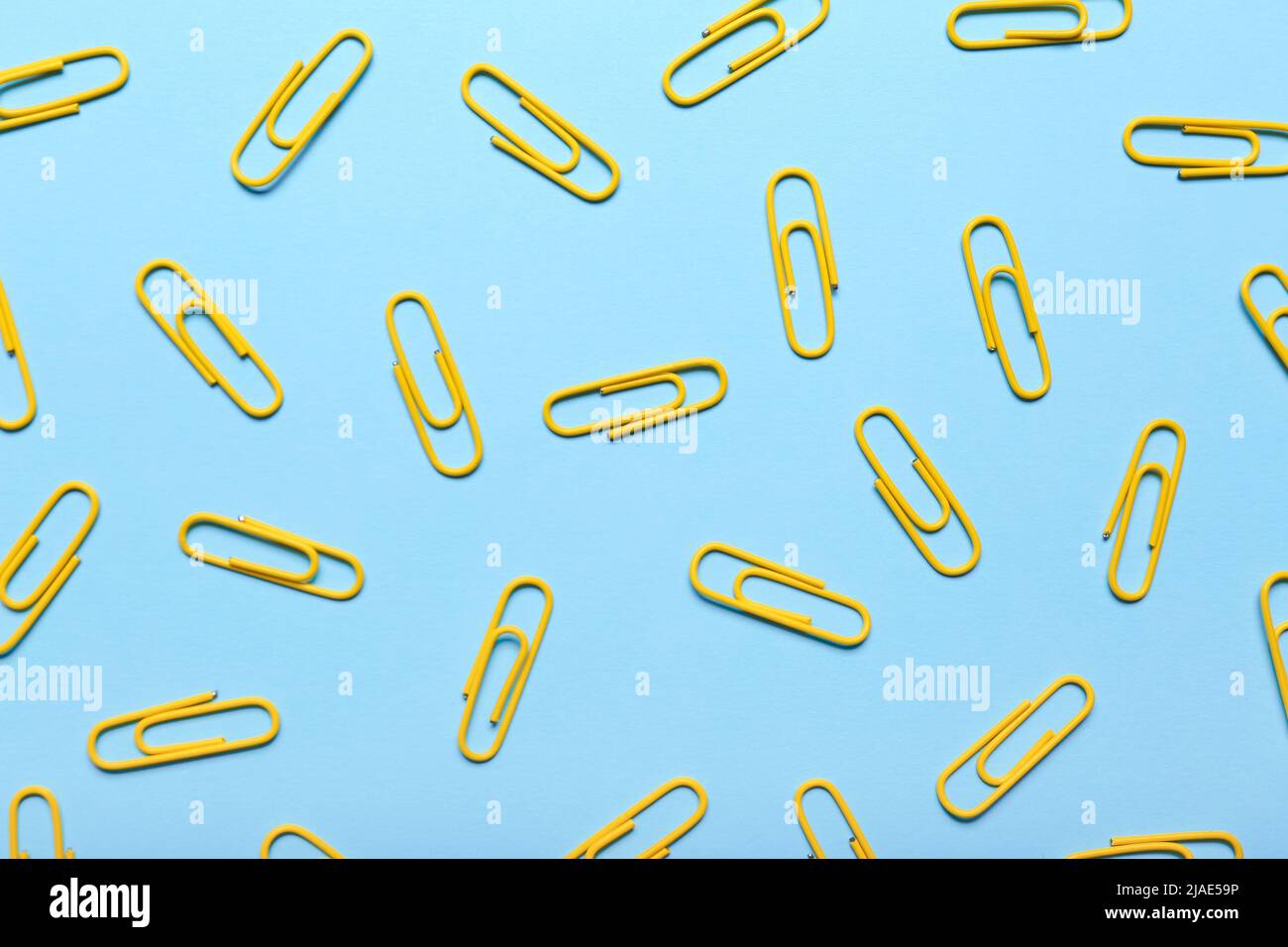 Yellow paper clips on blue background Stock Photo - Alamy