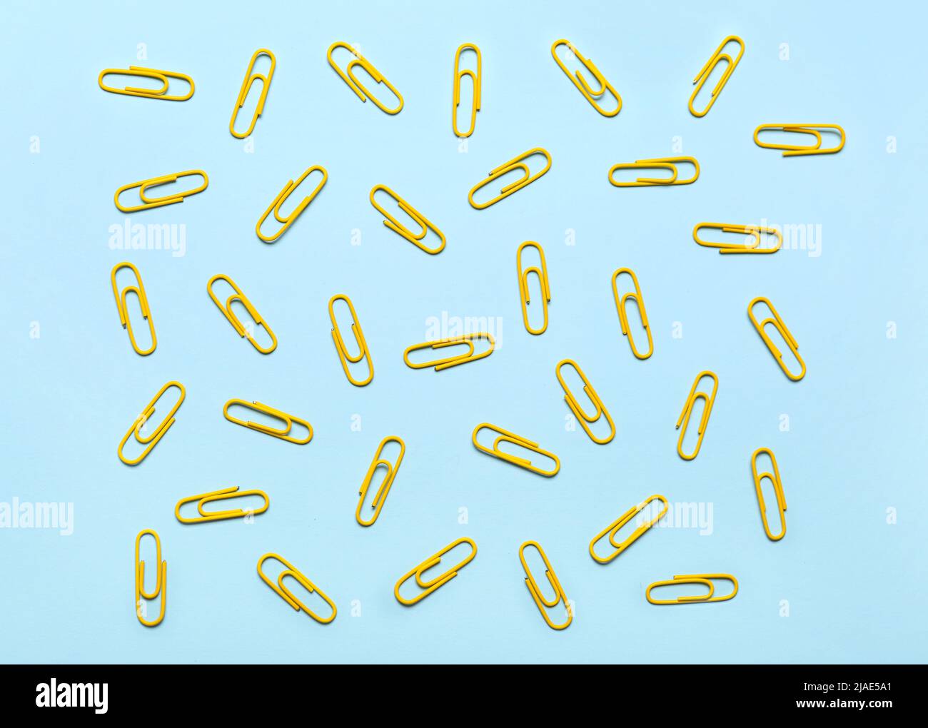 Yellow paper clips on blue background Stock Photo - Alamy