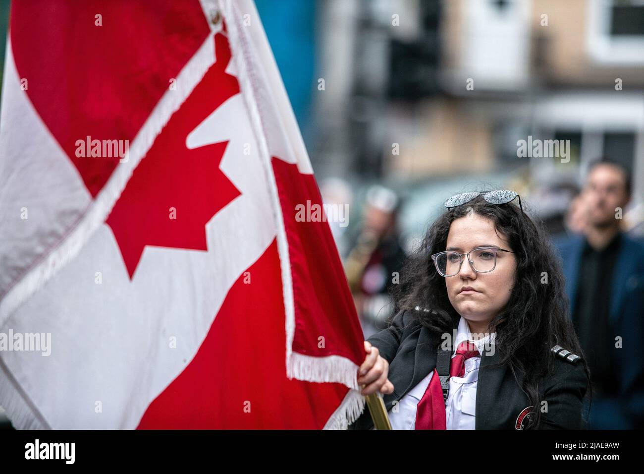 A flag-bearer carrying the Canadian flag at the forefront of the ...