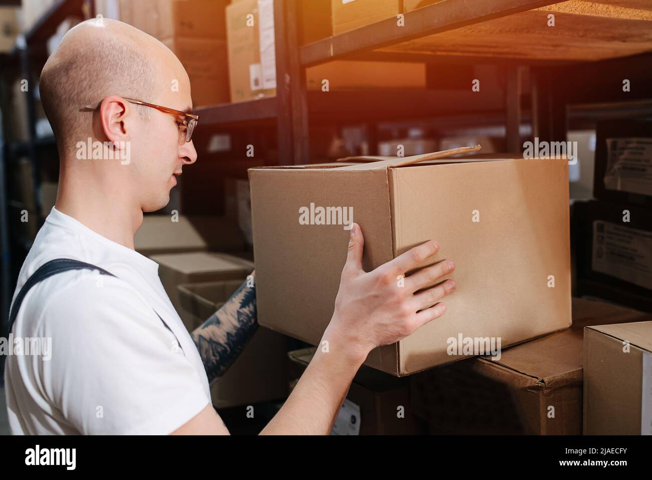 Mind absent male warehouse worker placing a box on the shelf, doing ...