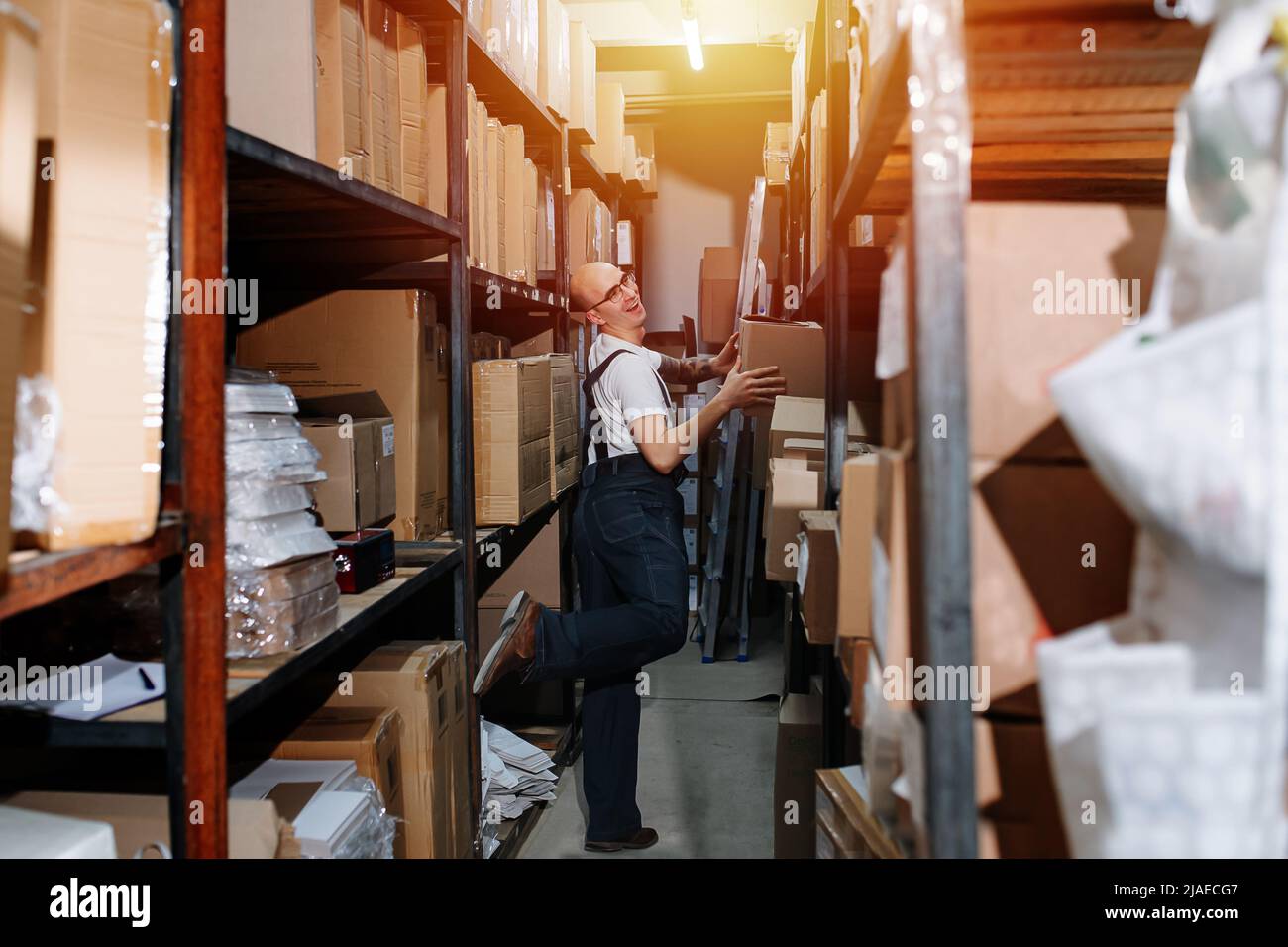 Playful funny male warehouse worker fooling around while holding a box ...
