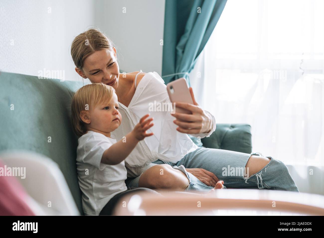 Young mother and cute baby girl using mobile phone at home Stock Photo ...