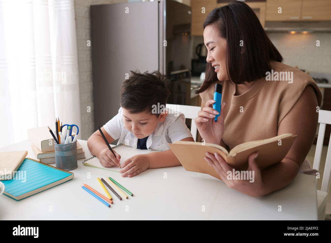 Smiling mother helping son with doing homework for school Stock Photo - Alamy