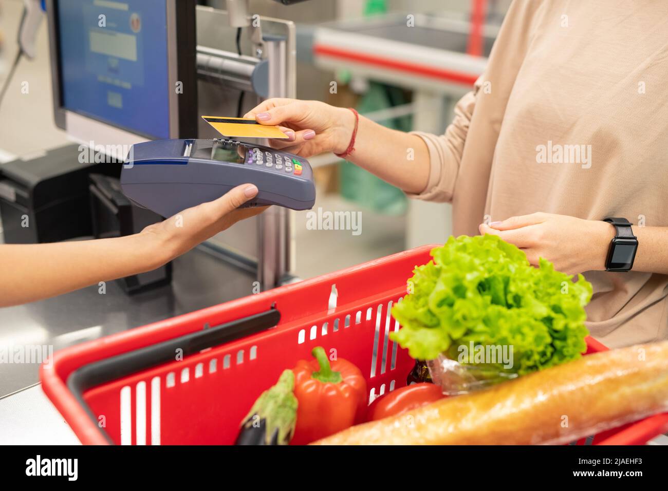 Unrecognizable young woman paying for foods in modern supermarket with ...