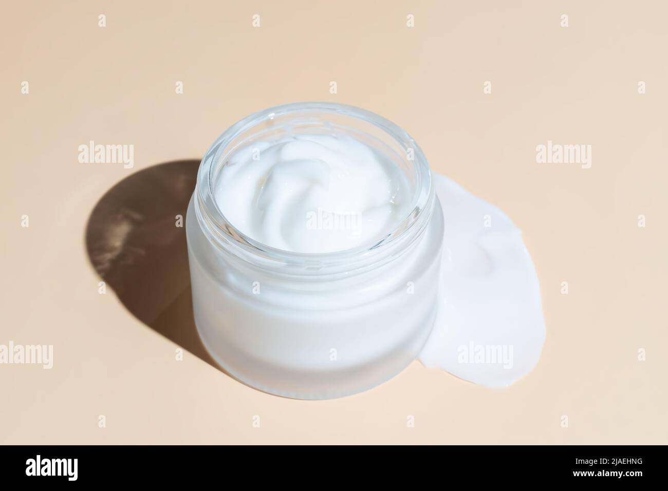Frosted glass jar of moisturizer cream on beigebackground. Natural eco ...